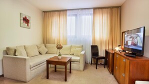 Uma sala de estar com sofá, mesa de centro, televisão e armário.