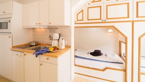 Uma cozinha compacta com armários brancos, micro-ondas e máquina de café.
