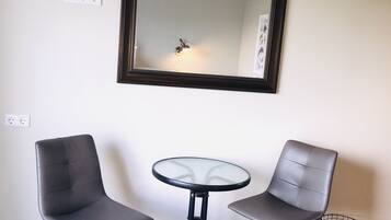 Quarto com duas cadeiras, uma mesa redonda pequena, um espelho na parede e uma tomada.