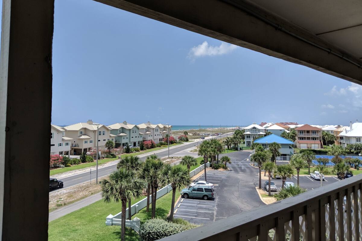 Vista de uma área residencial com edifícios altos, uma estrada e uma praia ao longe.