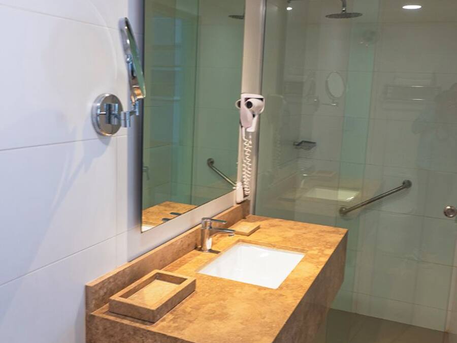 Casa de banho moderna com cabine de duche em vidro, um espelho grande e lavatório de mármore.