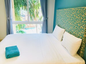 Quarto de hotel com cama, janela com cortinas e vista para uma piscina.