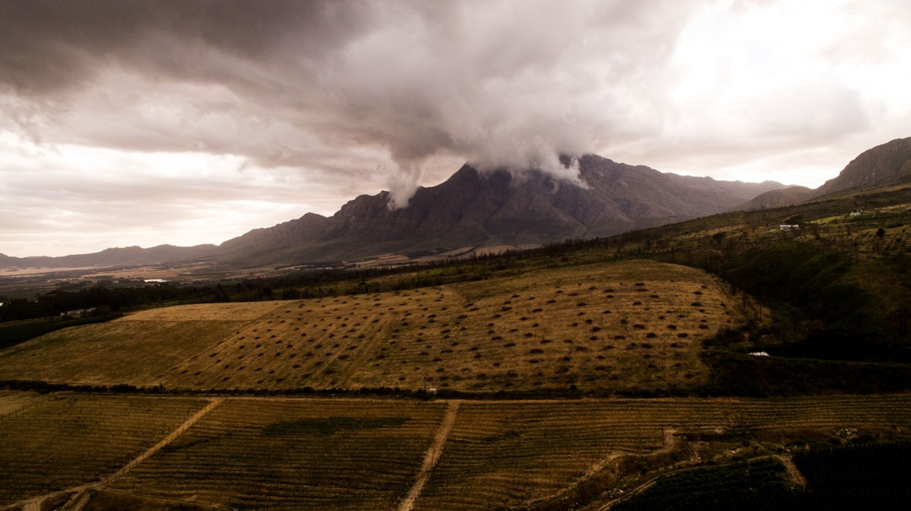 Paisagem montanhosa com campos e alguns edifícios no vale.