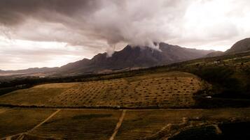 Paisagem montanhosa com campos e alguns edifícios no vale.