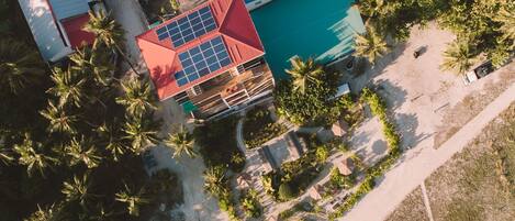 Vista aérea de um resort com um edifício de telhado vermelho, águas azul-claras e palmeiras.