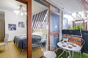 Quarto moderno com cama, uma cadeira e uma mesa com comida e bebidas.