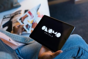 Uma pessoa segurando um tablet com o logotipo ONOMO HOTELS.