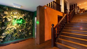 Uma escadaria com balaústres de madeira e uma parede verde com um letreiro neon.