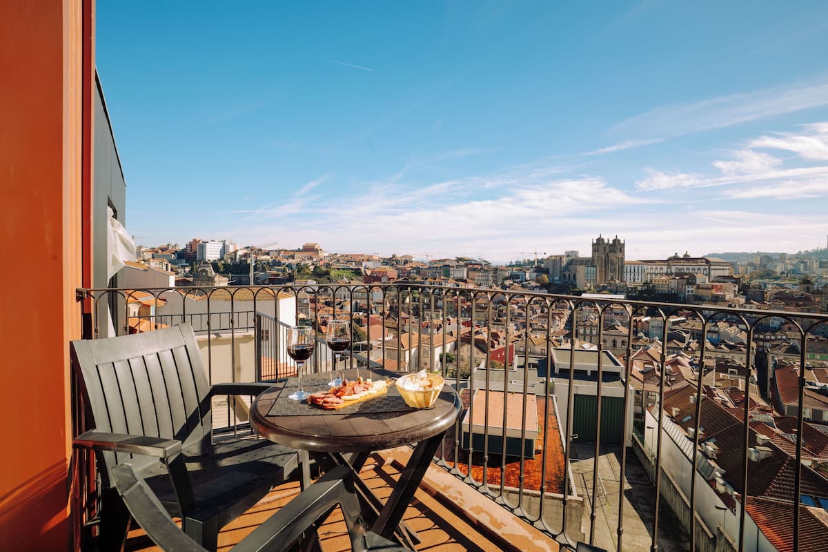 Uma varanda com mesa, cadeiras e vista para a cidade.