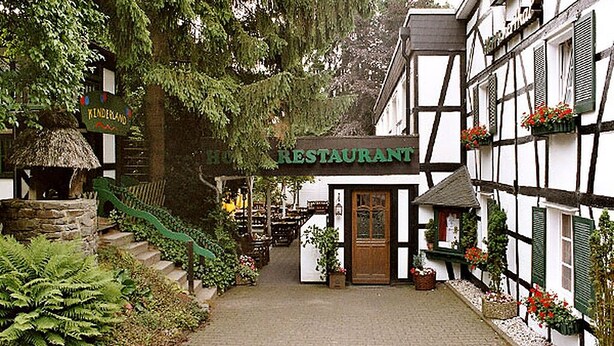 Edifício em estilo europeu tradicional, com uma placa que diz "RESTAURANT" e uma escadaria que leva a uma porta.