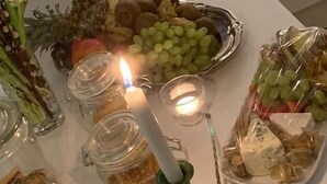 Uma mesa com diversos alimentos e uma vela acesa.