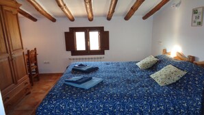 Quarto com cama, guarda-roupa de madeira e janela.