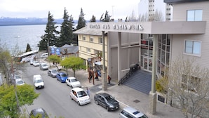 Um hotel com uma placa que diz 'HOTEL SOROS SARILOGH' e vista para a água e montanhas ao fundo.