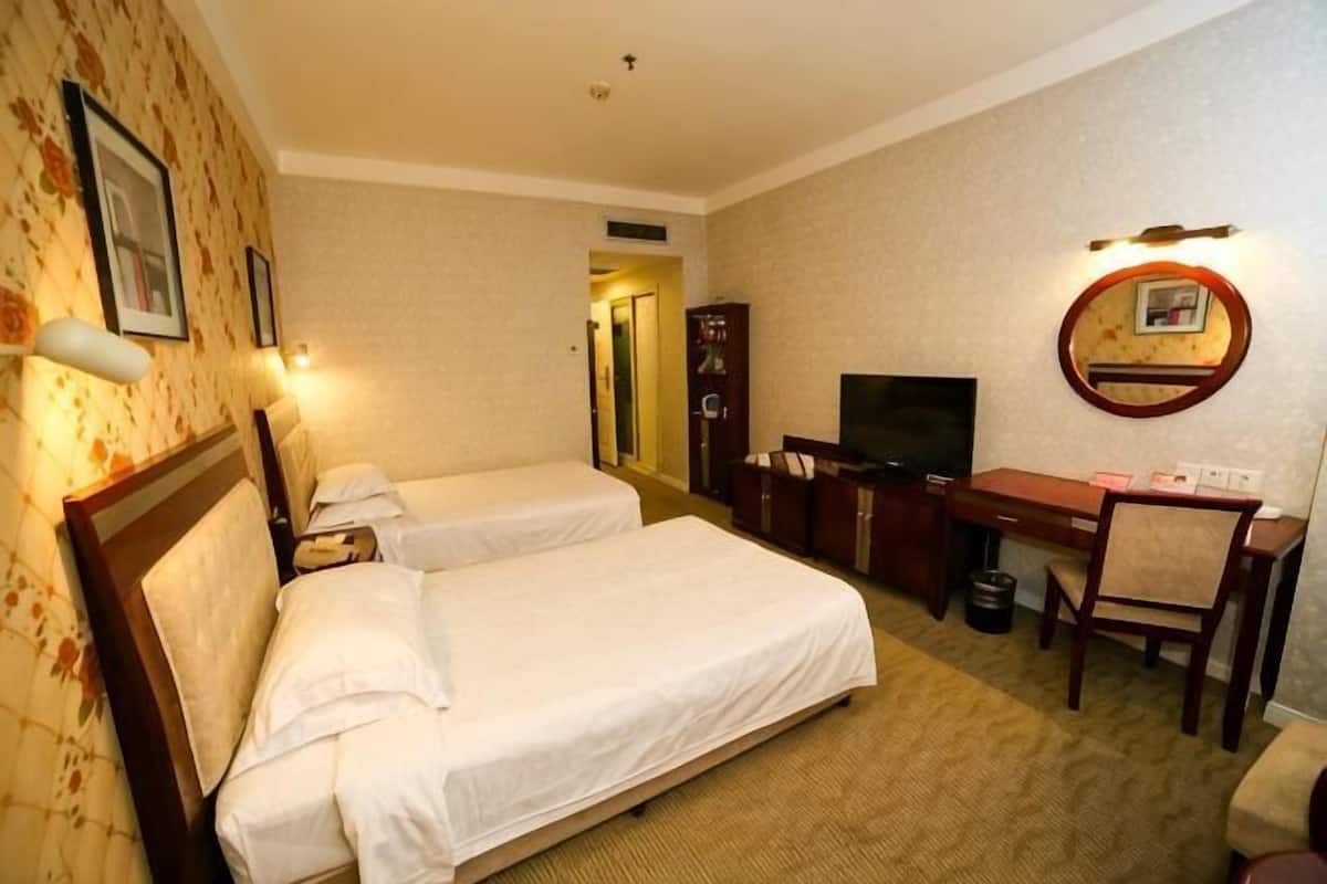 Quarto de hotel com duas camas, uma escrivaninha, uma televisão e um espelho.