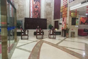 Uma área de recepção com piso de mármore, balcão e cadeiras.