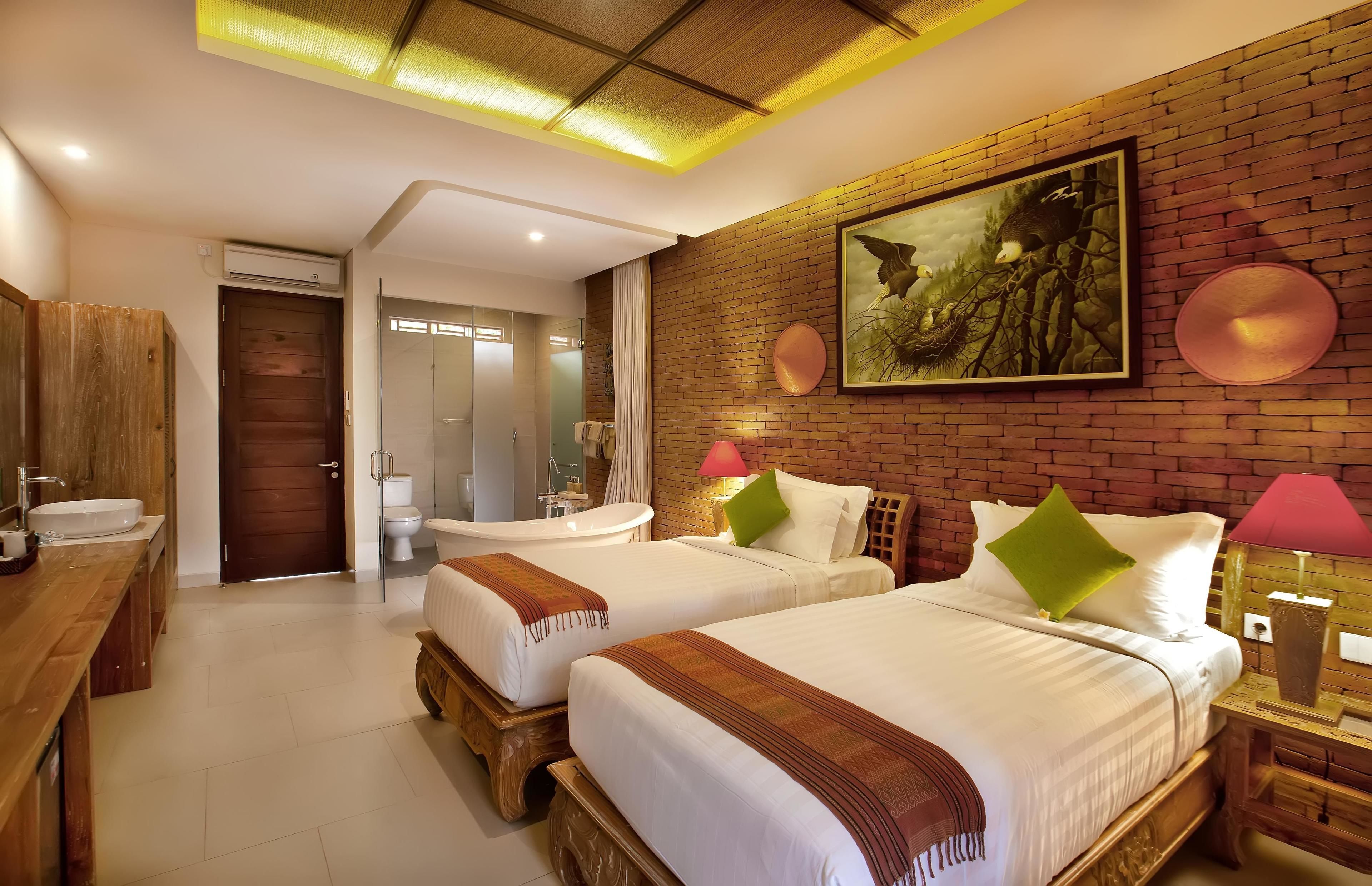 Quarto de hotel com duas camas, cômoda de madeira, banheiro com banheira e um quadro grande na parede.