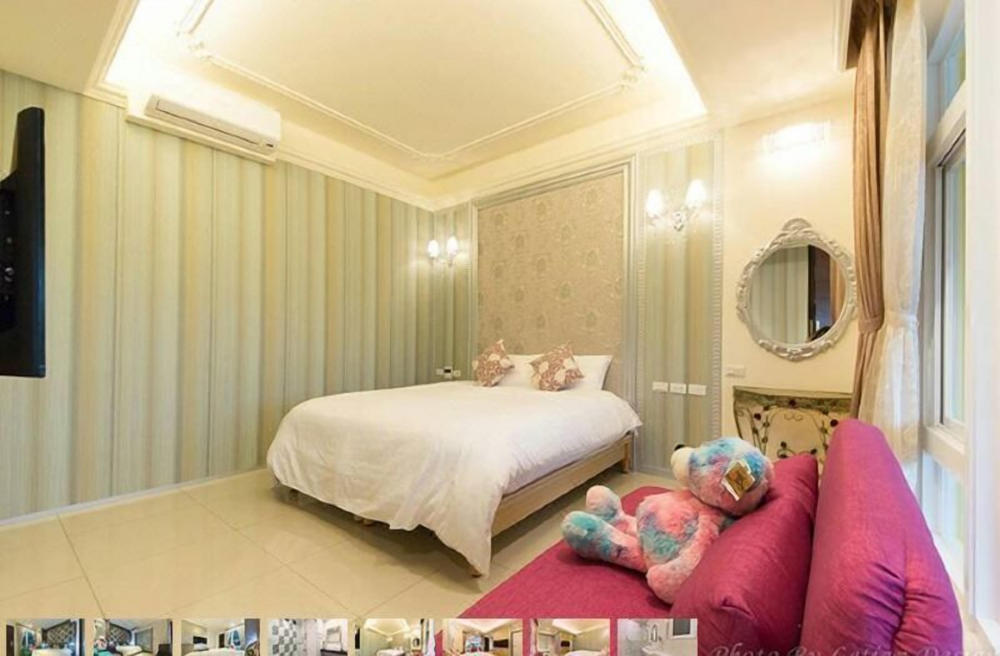 Quarto com cama, um espelho grande e um brinquedo fofinho em um sofá rosa.
