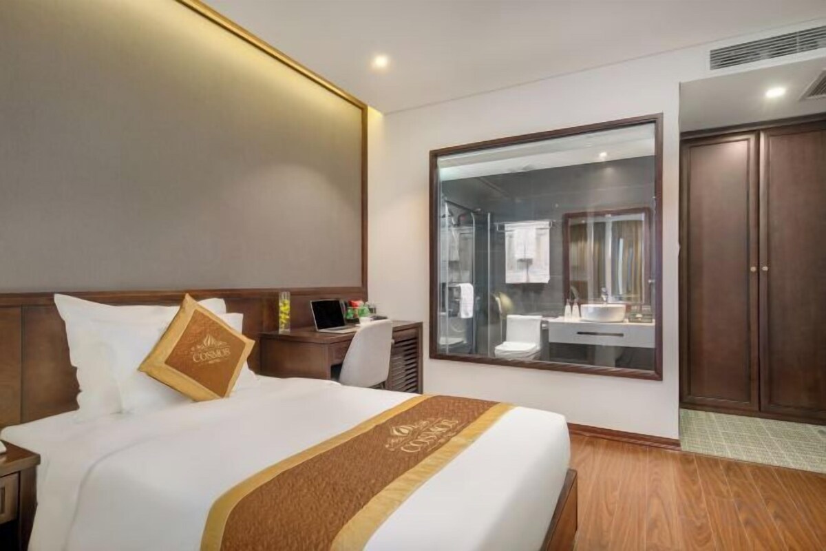 Quarto de hotel com uma cama grande, escrivaninha, espelho e guarda-roupa.