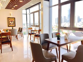 Uma sala de jantar moderna com grandes janelas, mesas de madeira e cadeiras confortáveis.