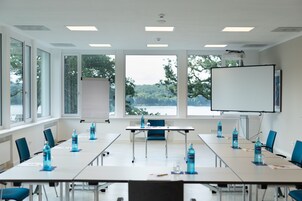 Uma sala de conferências com uma mesa comprida, cadeiras, um projetor e um quadro branco.