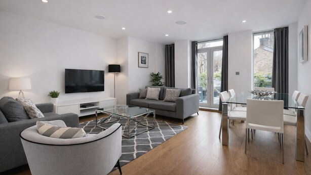 Uma sala de estar moderna com sofá, poltrona e mesa de centro de vidro. Há uma TV de tela plana na parede e uma mesa de jantar com cadeiras.