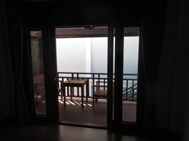 Varanda com mesa e cadeiras, vista do céu e guarda-corpo de madeira.