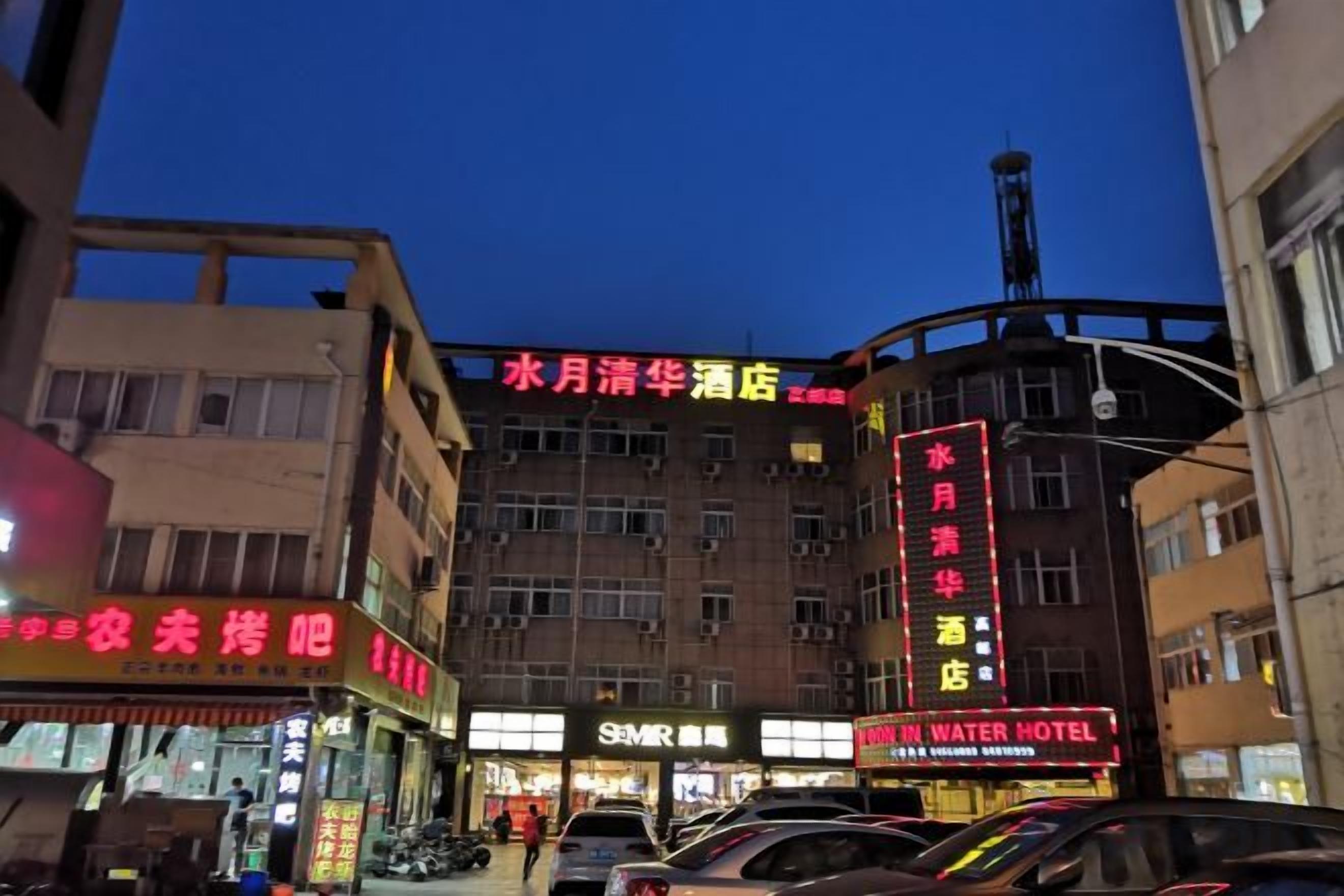 Um hotel com vários andares, uma torre d'água imponente e diversas placas iluminadas.