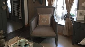 Um quarto aconchegante com uma cadeira, uma mesa com bandeja e cortinas.