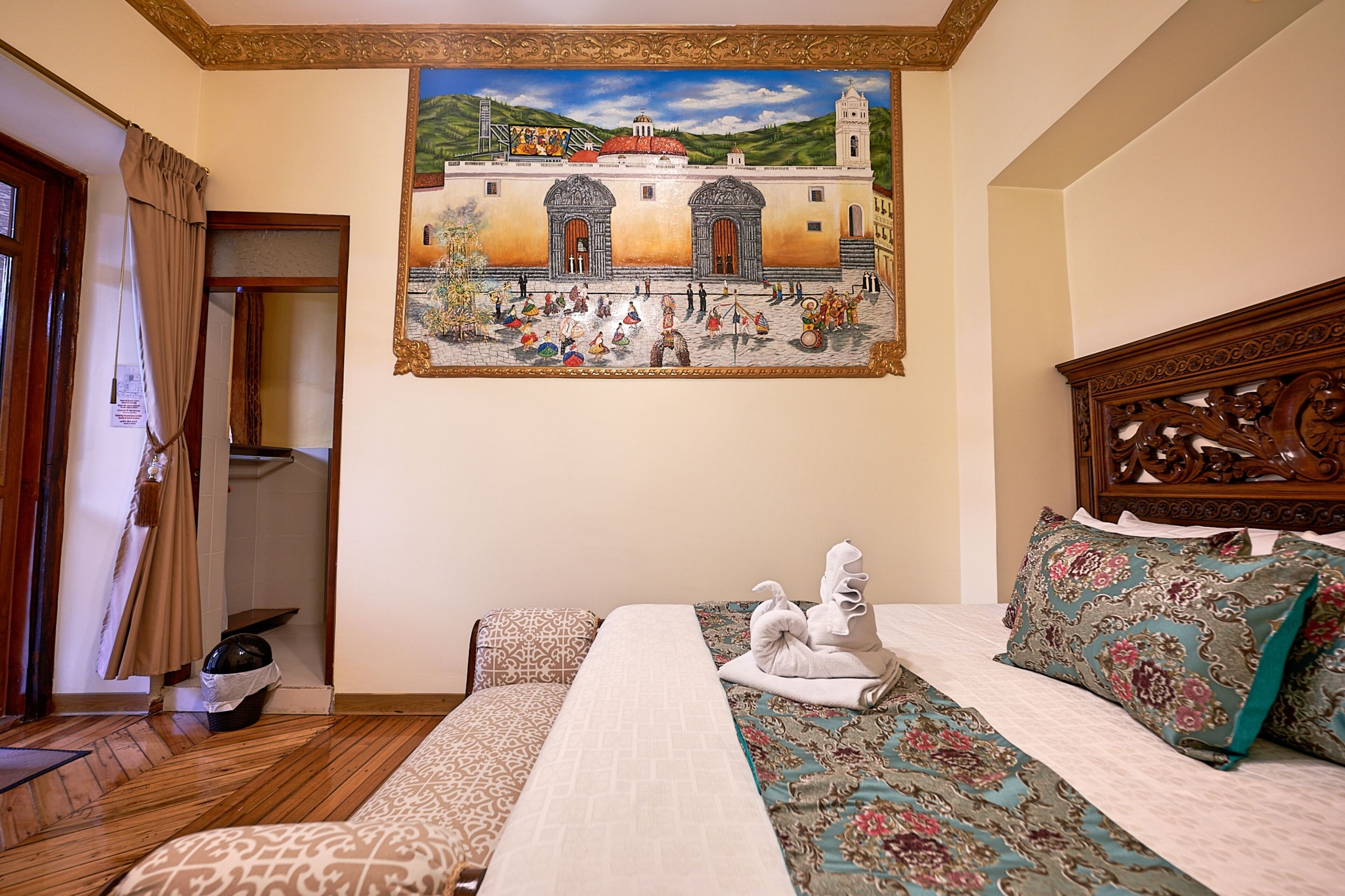 Quarto de hotel com uma cama, um quadro de um edifício histórico e uma cabeceira de madeira.
