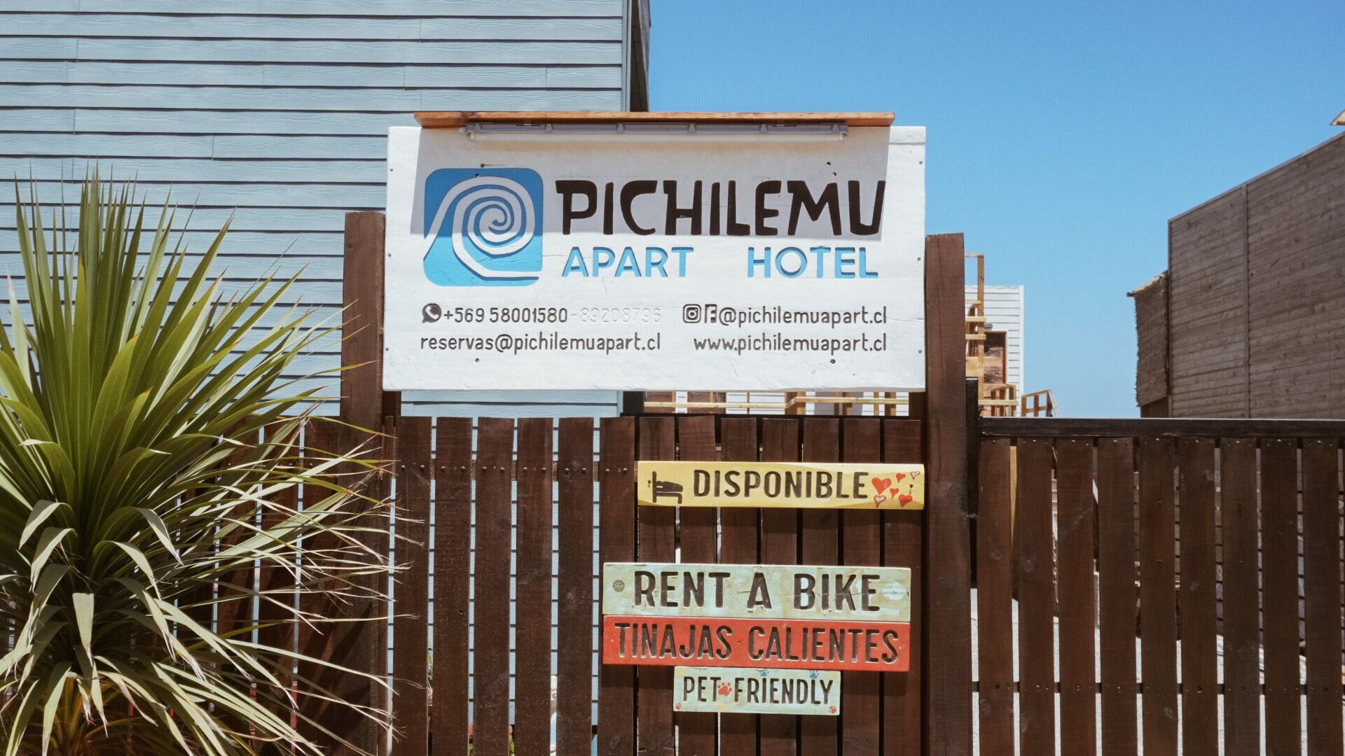 Placa do Pichilemu Apartment Hotel com informações de contato e um site.
