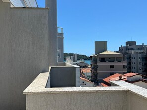 Terraço no telhado com vista para uma cidade costeira, com edifícios modernos e céu claro.