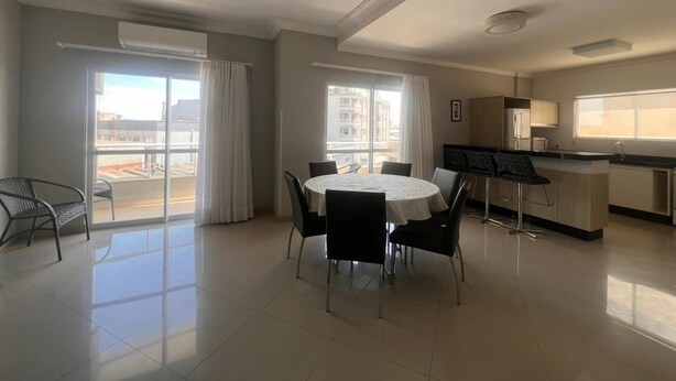 Um apartamento moderno com área de jantar, cozinha e varanda.