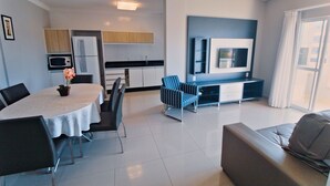 Um espaço moderno para viver com área de jantar, cozinha e espaço para sentar.