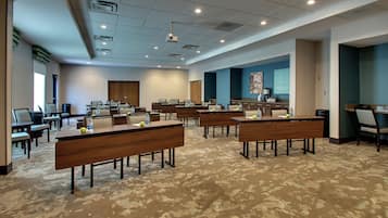 Sala de conferência com várias mesas e cadeiras, equipada com projetores e uma tela grande.