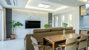 Uma área de refeições moderna com mesa e cadeiras de madeira, um sofá e plantas em vasos.