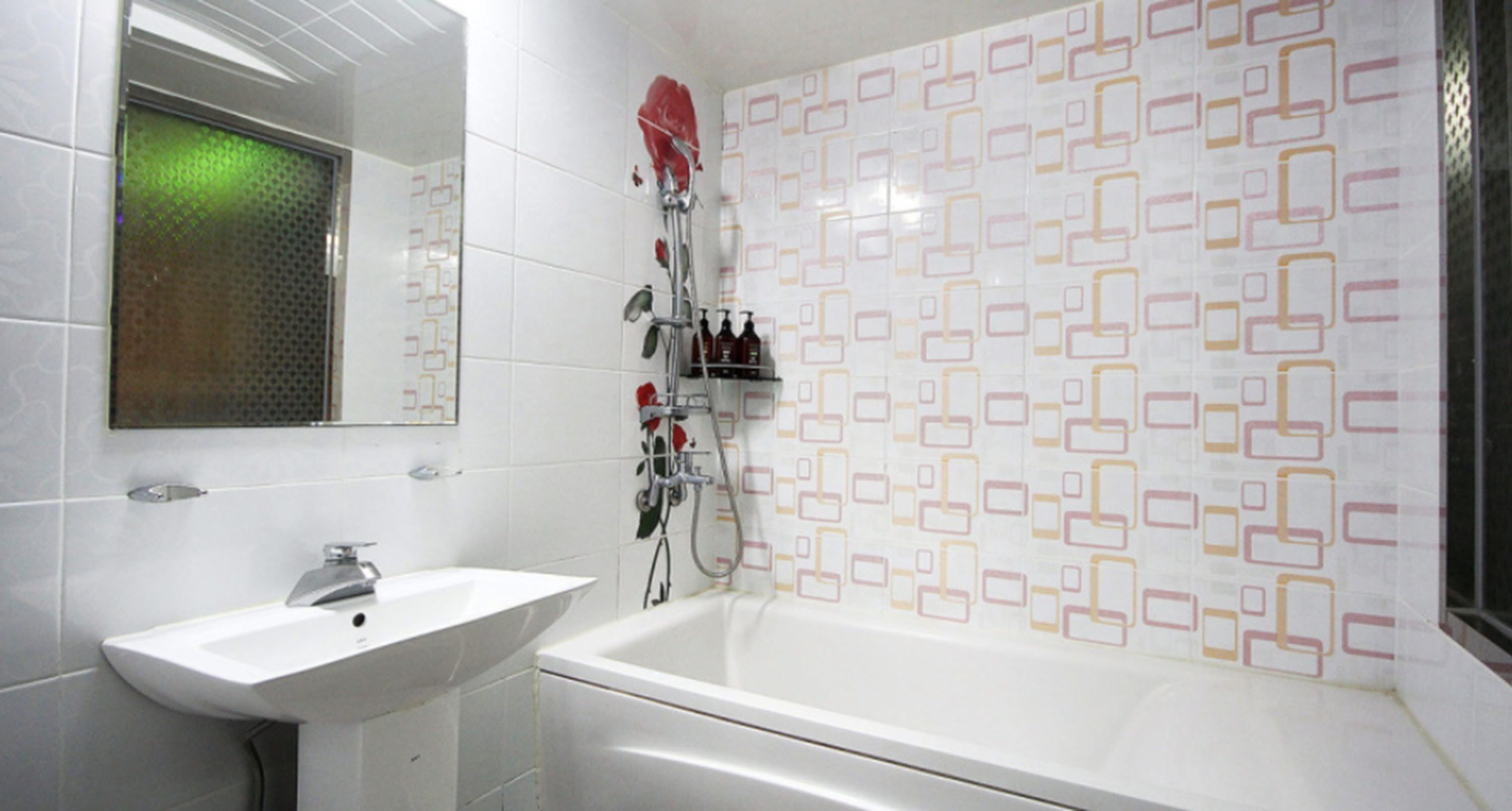 Casa de banho com lavatório branco, banheira e chuveiro decorado com motivos florais.