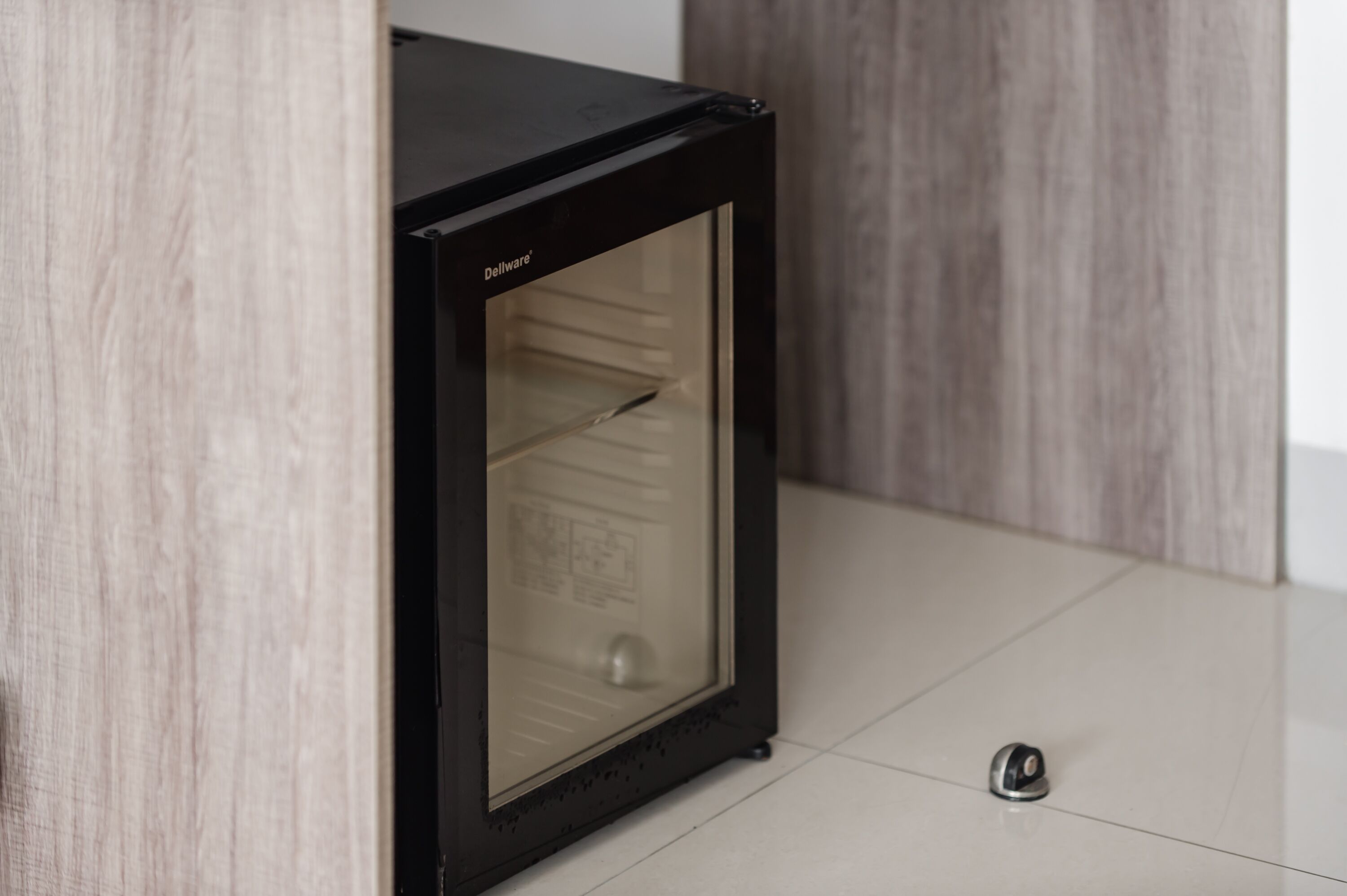 Um cofre preto com porta transparente, apoiado em um chão de azulejos.