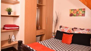 Quarto com cama, guarda-roupa e prateleira com uma planta.