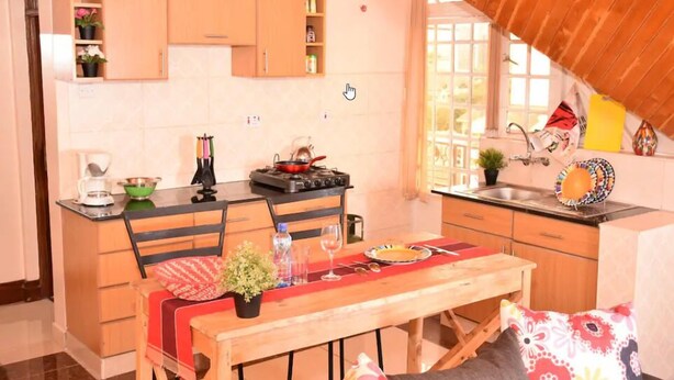 Uma cozinha compacta com armários de madeira, um fogão e um espaço de jantar com uma mesa posta para dois.