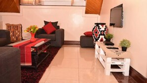 Uma sala de estar moderna com um sofá, mesa de centro e televisão na parede.