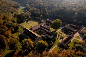 Vista aérea de uma propriedade histórica com vários edifícios, um pátio central e áreas arborizadas ao redor.