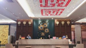 Uma receção com um relógio digital, um painel decorativo e dois taboretes de bar.