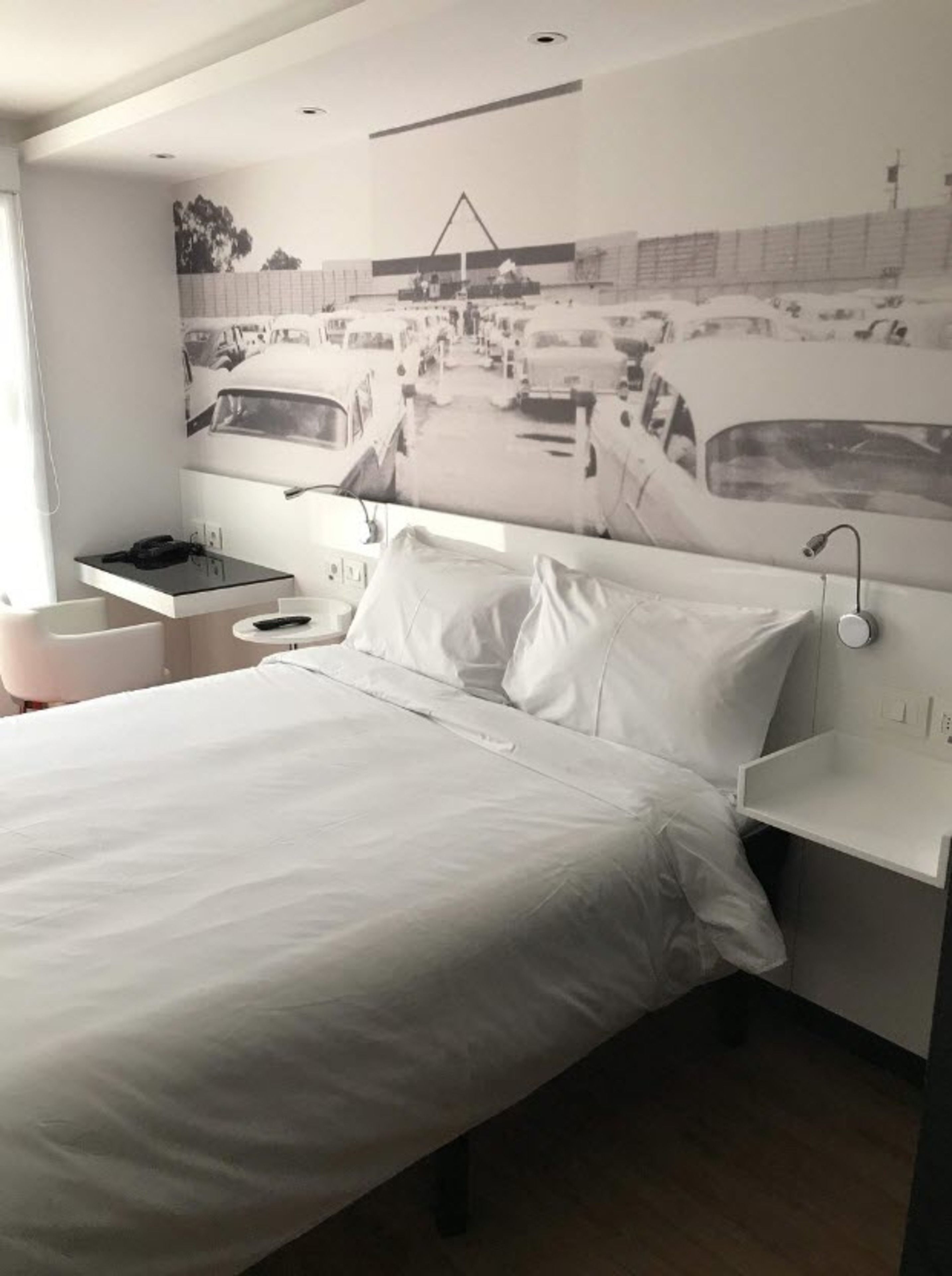 Quarto moderno com uma cama grande, mesa de cabeceira e televisão na parede.