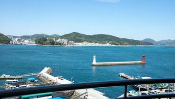Vista costeira com um cais, barcos e um farol.