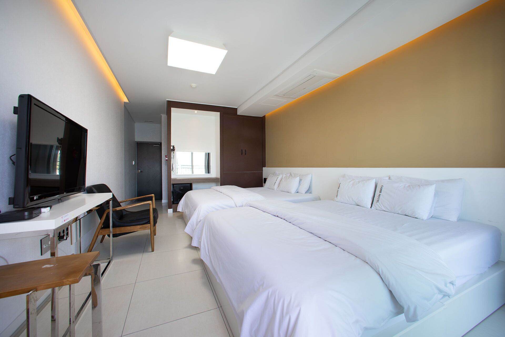 Quarto de hotel com uma cama grande, escrivaninha com televisão de tela plana, uma cadeira e guarda-roupa.
