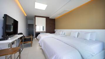 Quarto de hotel com uma cama grande, escrivaninha com televisão de tela plana, uma cadeira e guarda-roupa.