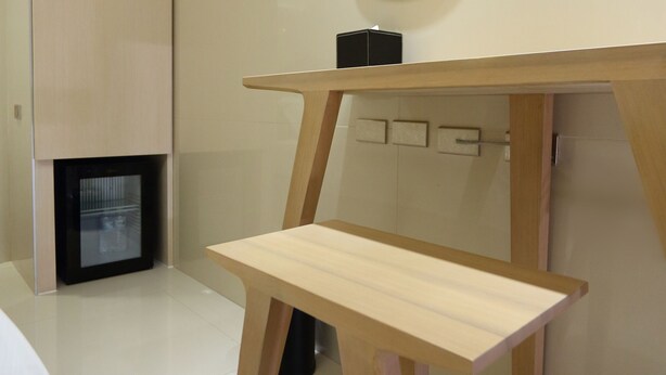 Quarto moderno com escrivaninha de madeira, um pequeno cesto de lixo preto e espelho fixado na parede.