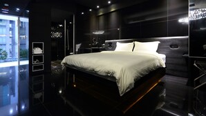 Quarto moderno com cama grande, mesa de cabeceira, espelho e vista para o exterior.