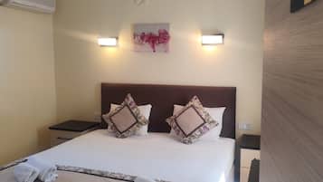 Quarto de hotel com cama, mesas de cabeceira, ar condicionado fixado na parede, um quadro e uma placa com o número '016'.