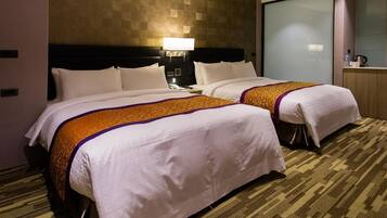 Quarto de hotel com duas camas, uma janela grande e uma luminária fixada na parede.